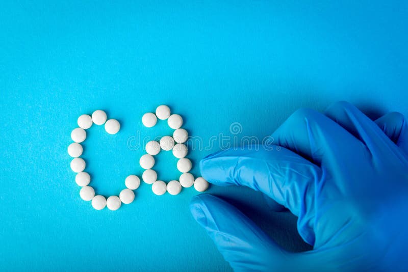 Hands in Gloves Making Calcium Symbol with White Pills on Blue ...