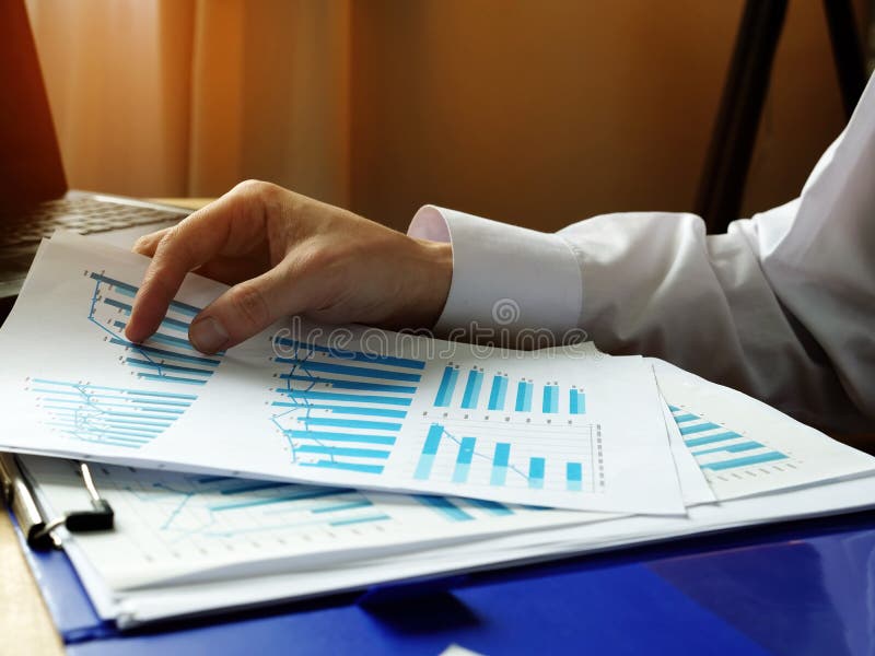 Hands Hold Papers with Graphs about the Financial Results of Company ...