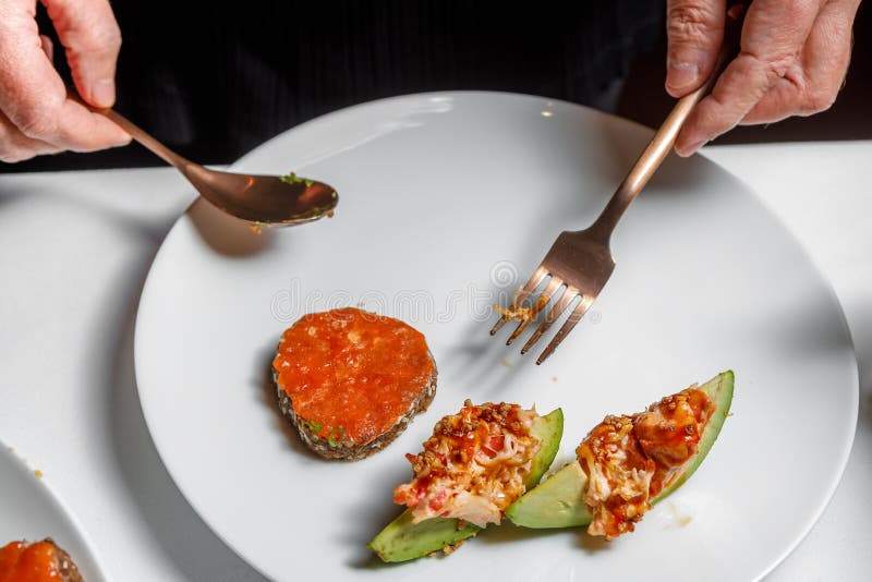 Hands Hold a Spoon and Fork Over a Plate with a Light Snack of Avocado ...