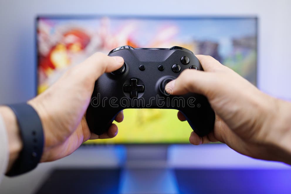 Hands Hold a Video Game Controller in Front of the Monitor Stock Image ...