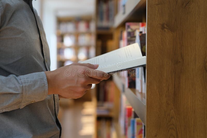 Hands Holding Book Close To Book Shelf in Library Stock Image - Image ...