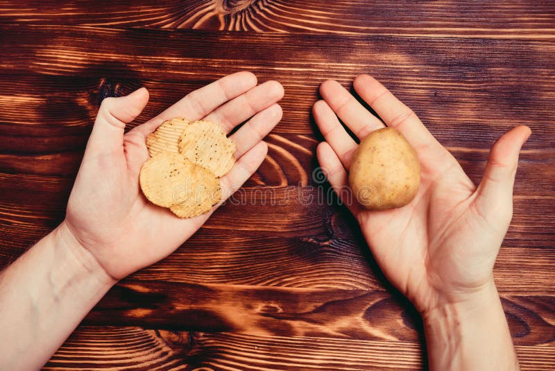 Hands Holding Chips and Potatoes on a Wooden Background. Top View Stock ...