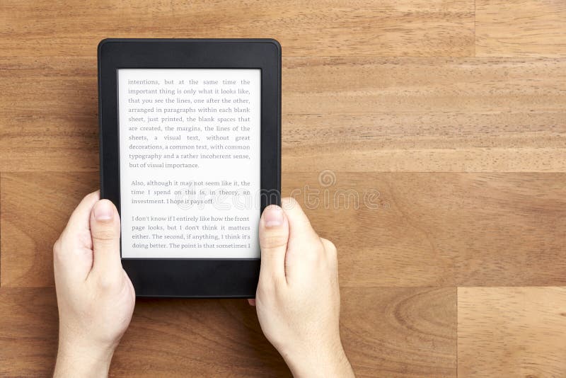 Hands Holding an Electronic Reader with Text on the Screen on a Wooden ...