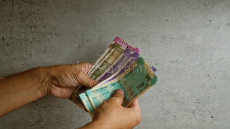 Hands Holding Indian Rupee Banknotes Against a Gray Concrete Wall ...