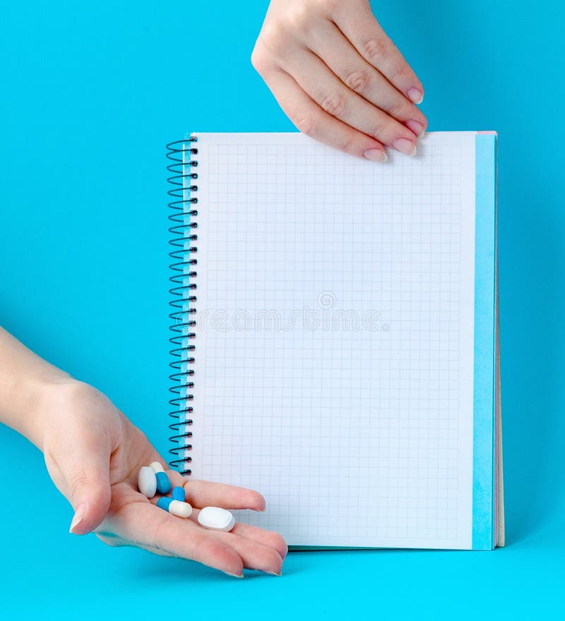 Hands Holding Pills and Notebook on a Blue Background Stock Image ...