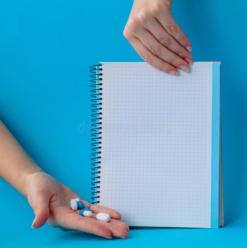 Hands Holding Pills and Notebook on a Blue Background Stock Image ...