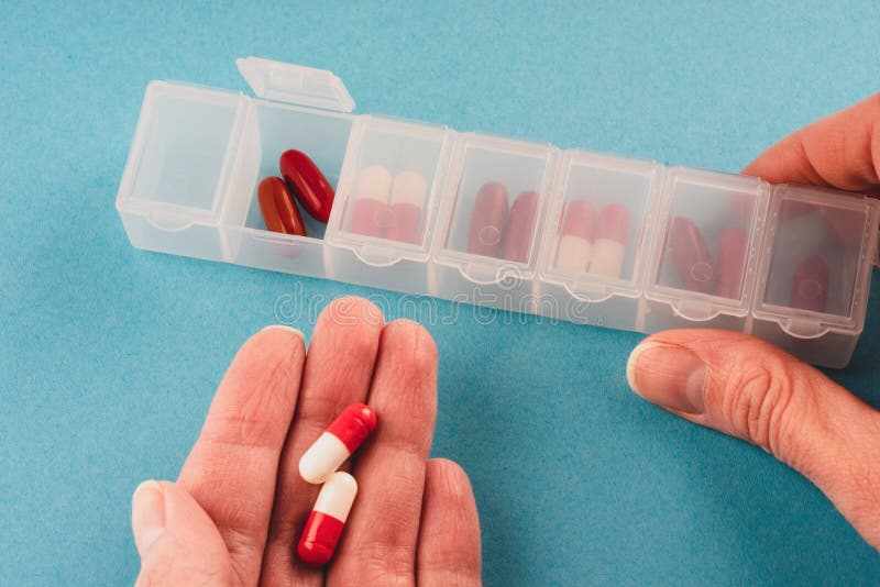 Hands Holding a Plastic Organizer Pill Box for the Week White on a Blue ...