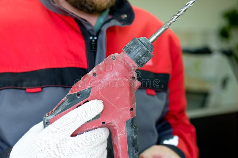 In the Hands of the Installer Worker Perforator Red with Traces of ... In the Hands of the Installer Worker Perforator Red with Traces of ...