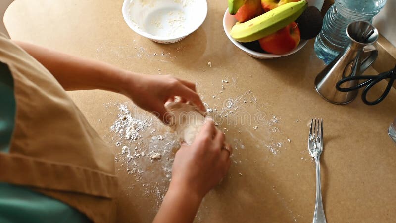Hands Kneading Dough on a Flour-Dusted Counter with Fruits Nearby in a ...