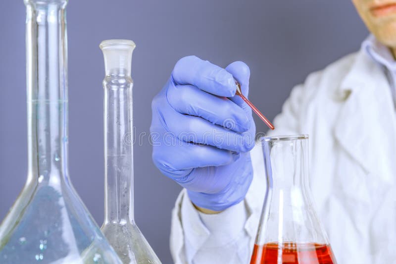 Hands of a Lab Technician with a Tube of Blood Sample and a Rack with ...