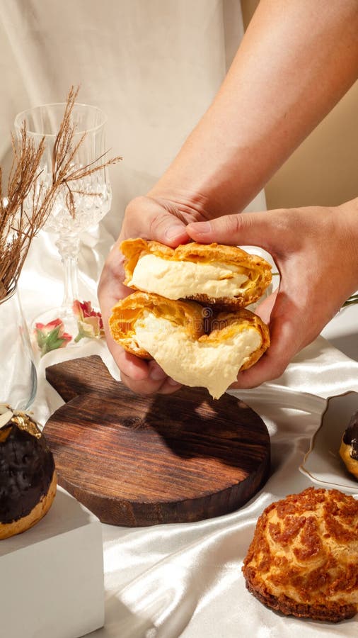Hands Lift a Delectable Pastry Filled with Cream, Surrounded by Various ...