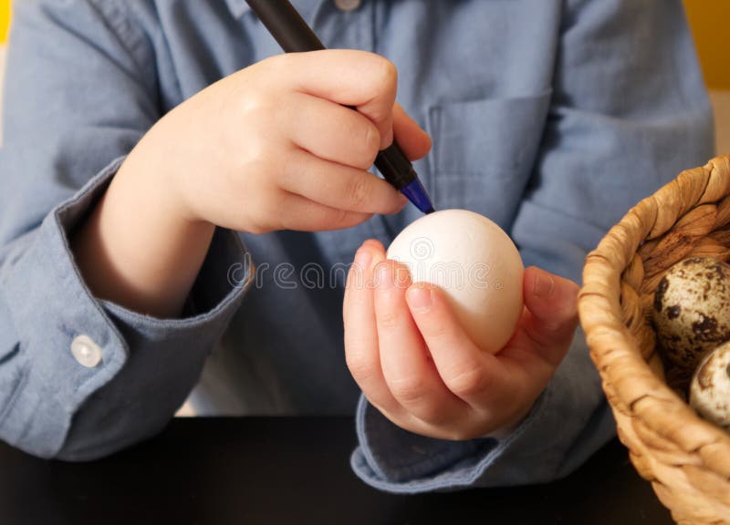 The Hands of a Little Boy Hold a Chicken Egg and a Felt-tip Pen and ...