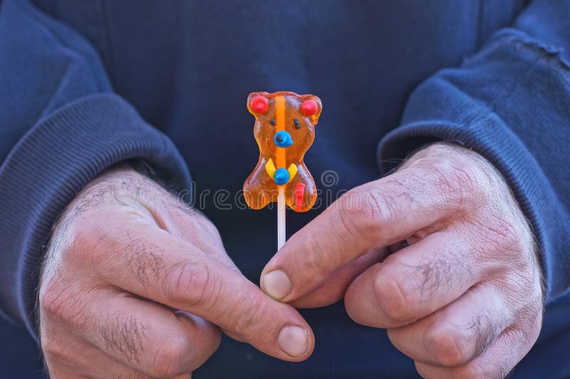 The Hands of a Man in Blue Clothes Hold with His Fingers a Red Gummy ...