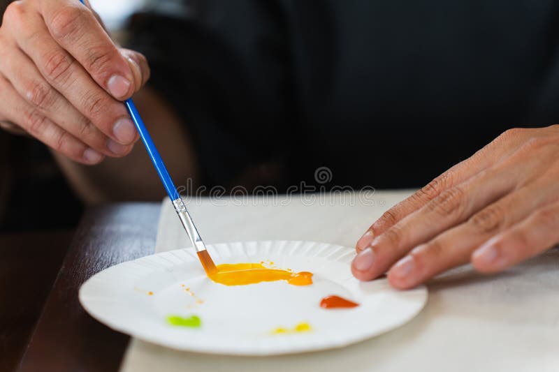 Hands of a Man Picking Up Paint with a Brush from the Color Palette ...