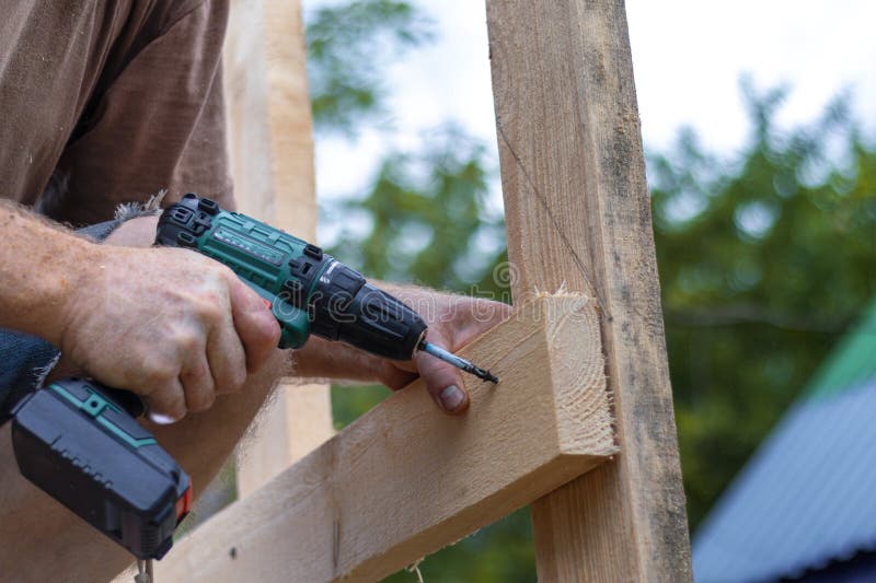 Hands of Man Using Drill To Assemble Wooden Structure. Precision and ...