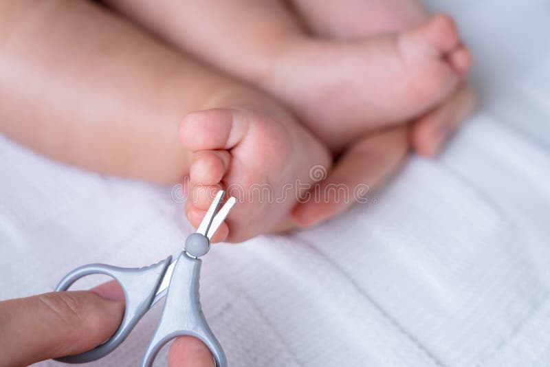 The Hands of a Mother with Scissors Make a Pedicure for a Newborn Child ...