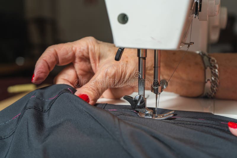 Hands of a Older Female Seamstress Sewing a Pair of Pants on a Sewing ...