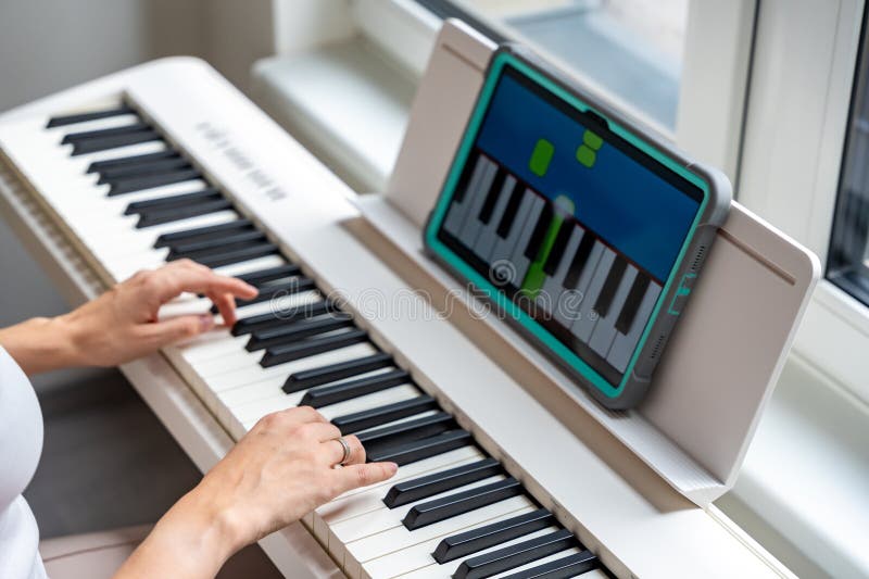 Hands Playing a Keyboard while Following an Interactive Learning App on ...