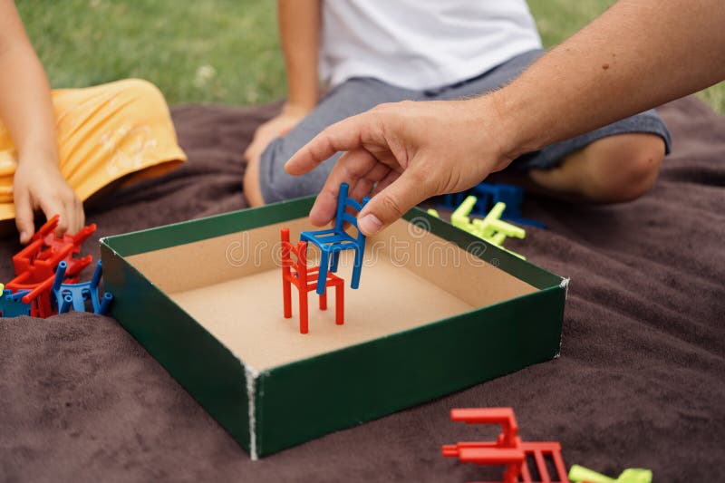 Hands Playing a Stacking Game with Colorful Plastic Chairs Outdoors ...