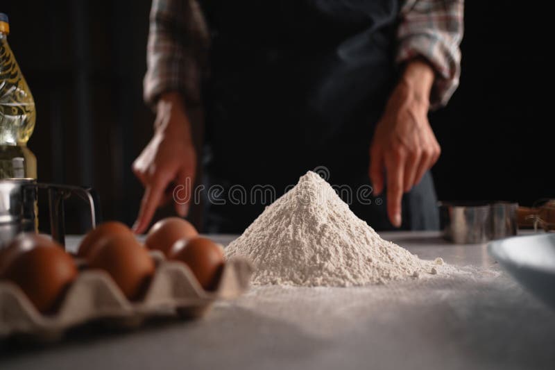 Hands Pointing at Pile of Sifted Flour on Table Surrounded by Eggs ...