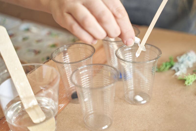 Hands Preparing Resin Mixture with Wooden Sticks in Clear Plastic Cups ...