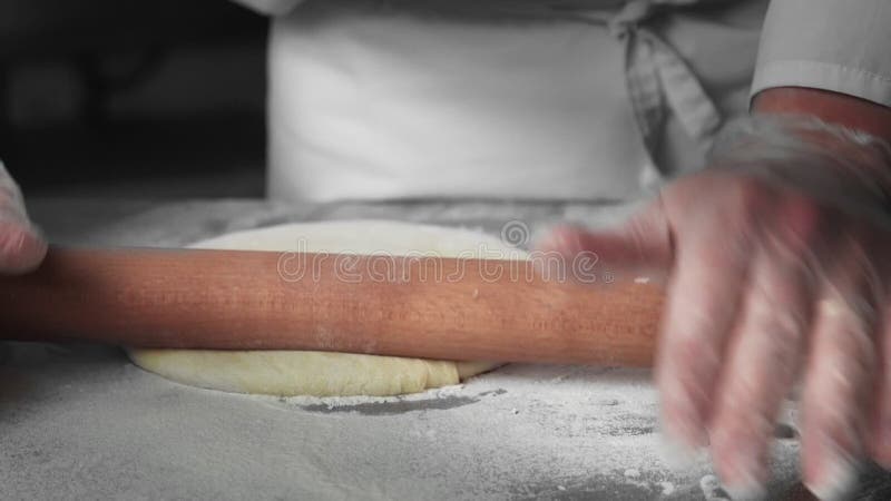 Hands of a Professional Baker Roll Out the Dough with a Rolling Pin on ...