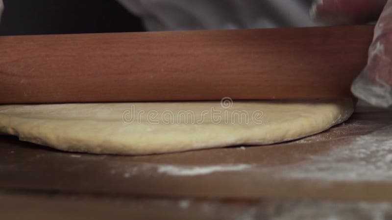 Hands of a Professional Baker Roll Out the Dough with a Rolling Pin on ...