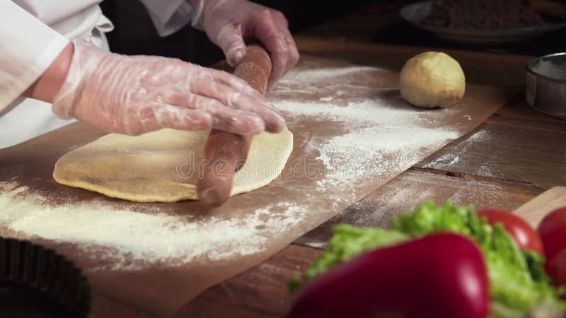 Hands of a Professional Baker Roll Out the Dough with a Rolling Pin on ...
