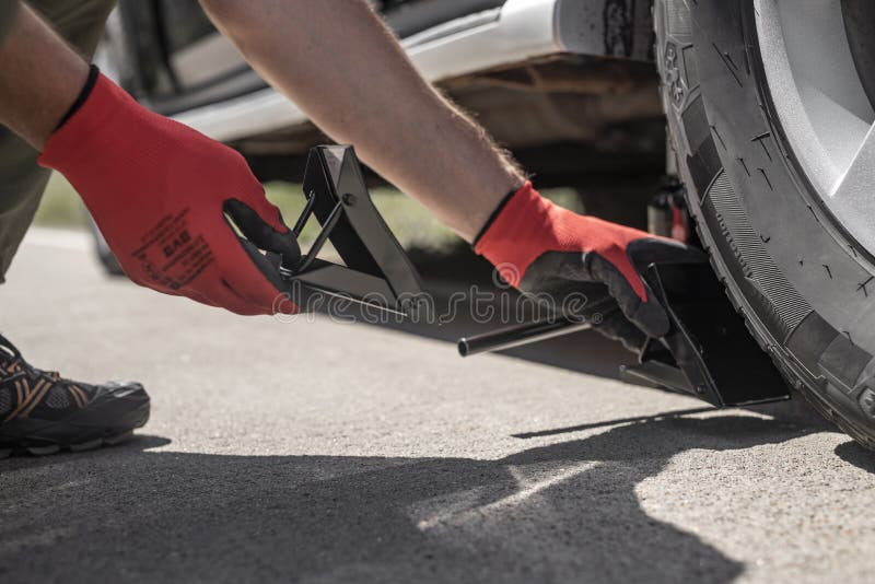 Hands Putting Wheel Chocks Under Car Tyre on Road, Bottom View Stock ...
