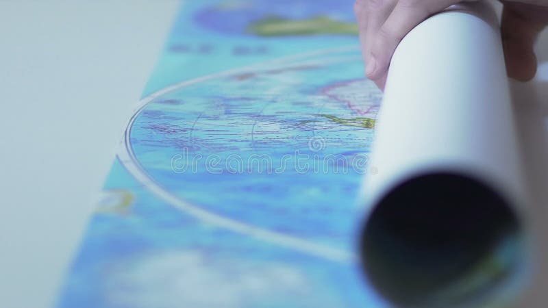 Hands Rolling Up World Map Poster and Taking it Away from the Table ...