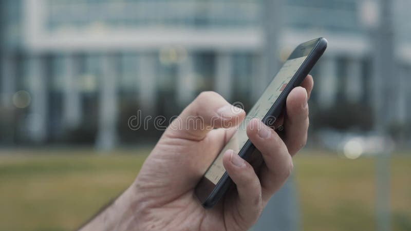 Hands Scrolling the Phone on Background of Blurred Business Buildings ...