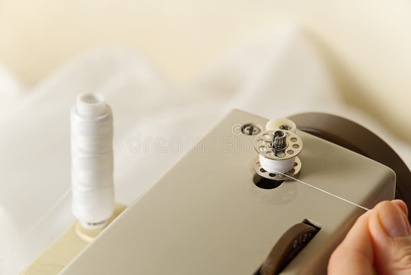 Hands of a Seamstress Winding Thread from a Spool To a Bobbin, Close-up ...