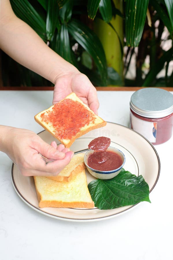 Hands Spreading Plum Jam on a Toast Against Jar with Jam Stock Image ...