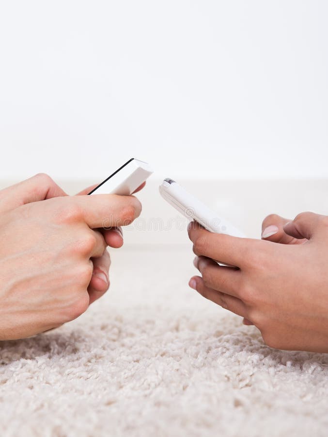 Hands Text Messaging through Smartphones on Rug Stock Image - Image of ...