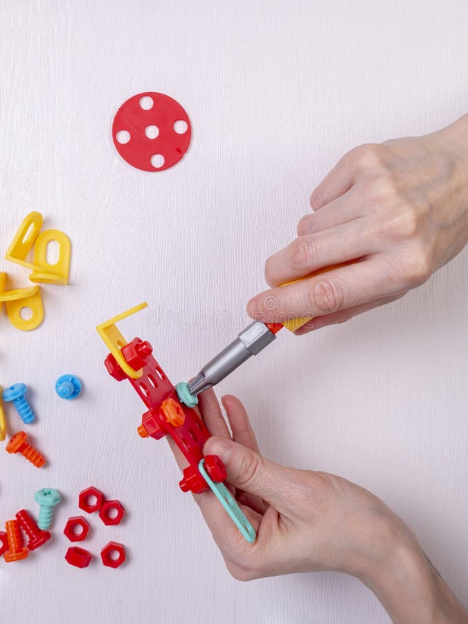 Hands Tightening a Nut with a Screwdriver on a Children S Plastic ...