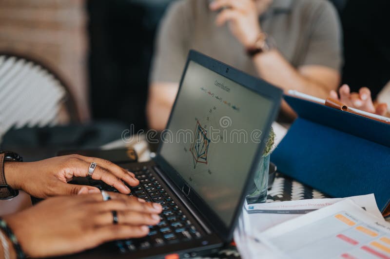 Hands Typing on Laptop in a Business Meeting with Charts and Documents ...