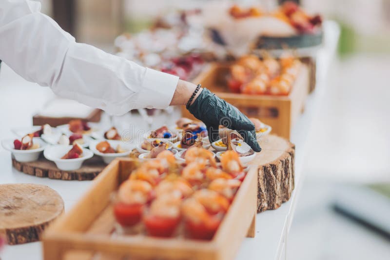 Hands of a Waiter Prepare Food for a Buffet Table. Caterer Arranges ...