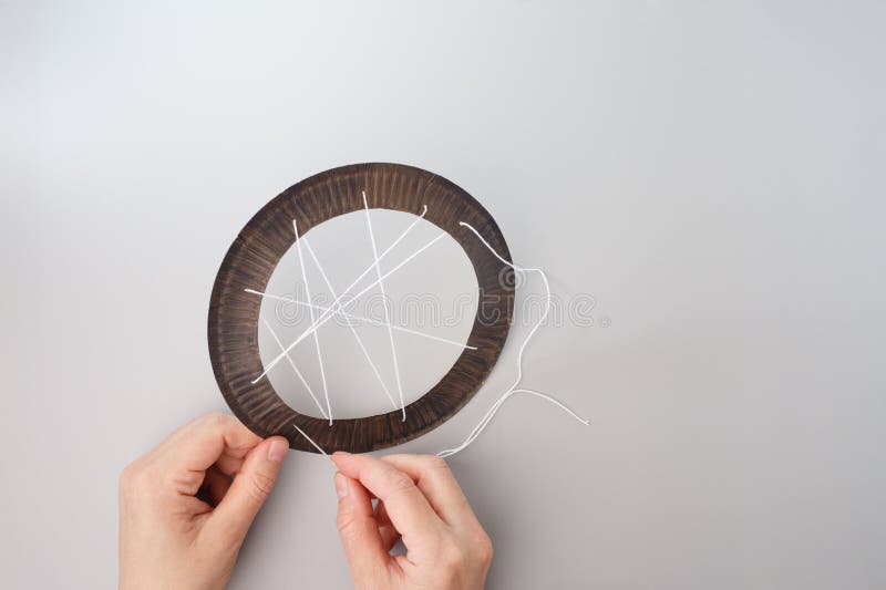 Hands Weaving White String through Holes in Round Brown Paper Plate To ...