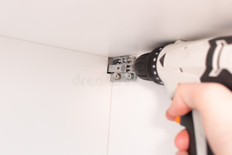 Hands of a Worker Installing a Fasteners for Kitchen Drawers To the ...