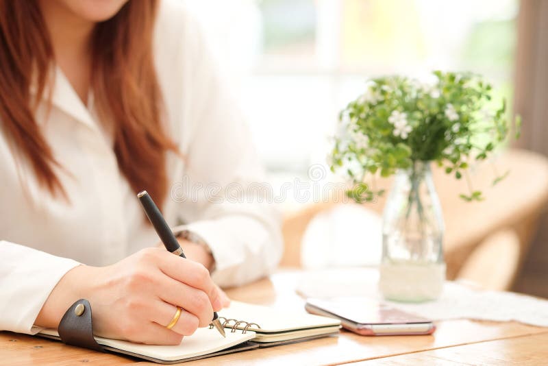 Hands of a Working Beautiful Woman are Writing a Note on Her Booklet at ...