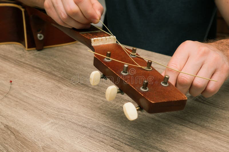 Hands of a Young Man Changing the String on an Acoustic Guitar. Hand ...
