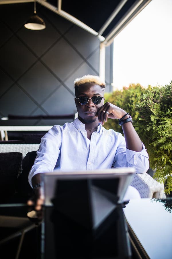 Handsome Afro American Man is Using a Tablet, Smiling while Sitting on ...