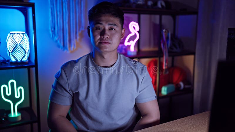 Handsome Asian Man with Neutral Expression in a Dark Illuminated Gaming ...