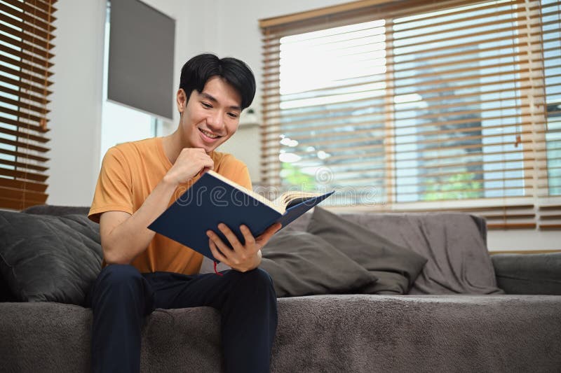 Handsome Asian Man Reading Book on Couch at Home. Hobby, Leisure and ...