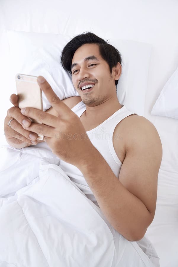 Handsome Asian Man Using a Cellphone while Lying Down Stock Image ...
