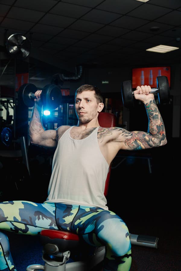 Handsome Athletic Man Training His Shoulders with Dumbbells Sitting on ...