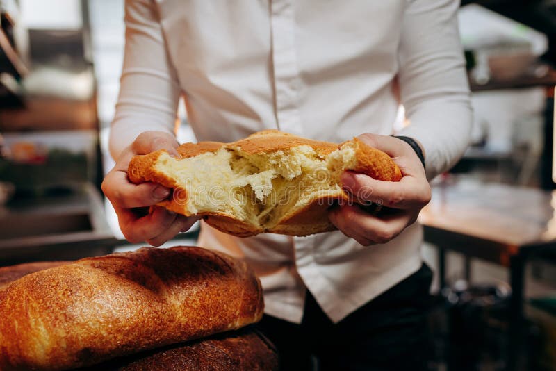 Baker in Uniform Breaks Freshly Baked Bread at the Bakery Stock Photo ...