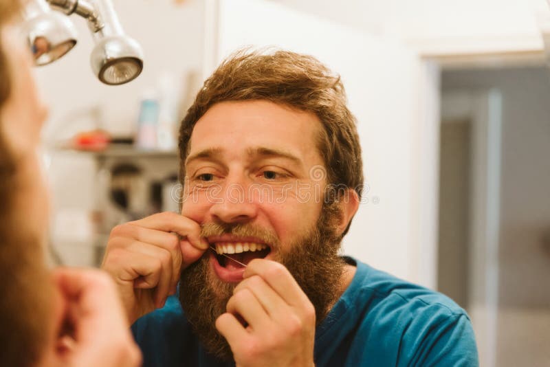 Handsome Bearded Man Looking at Mirror while Using Dental Floss in ... Handsome Bearded Man Looking at Mirror while Using Dental Floss in ...