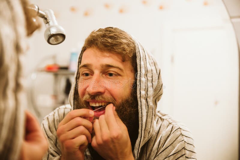 Handsome Bearded Man Looking at Mirror while Using Dental Floss in ... Handsome Bearded Man Looking at Mirror while Using Dental Floss in ...
