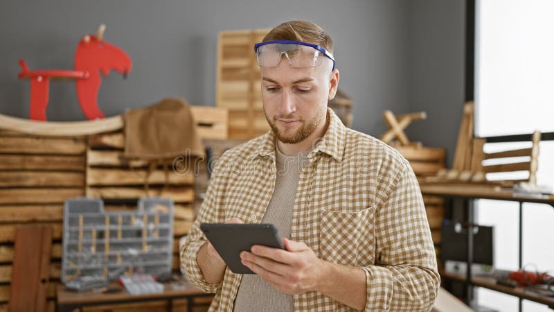 Handsome Bearded Man in Safety Goggles Using Tablet in Wood Workshop ...
